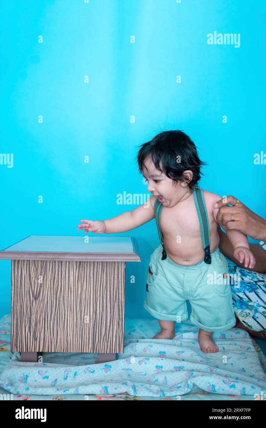 Smiling six months old cute indian baby boy trying to stand with ...
