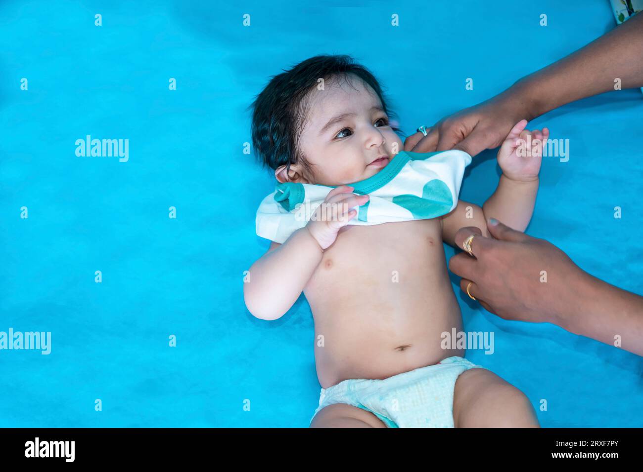 Indian mother changing cloths of cute six months old baby boy wearing ...