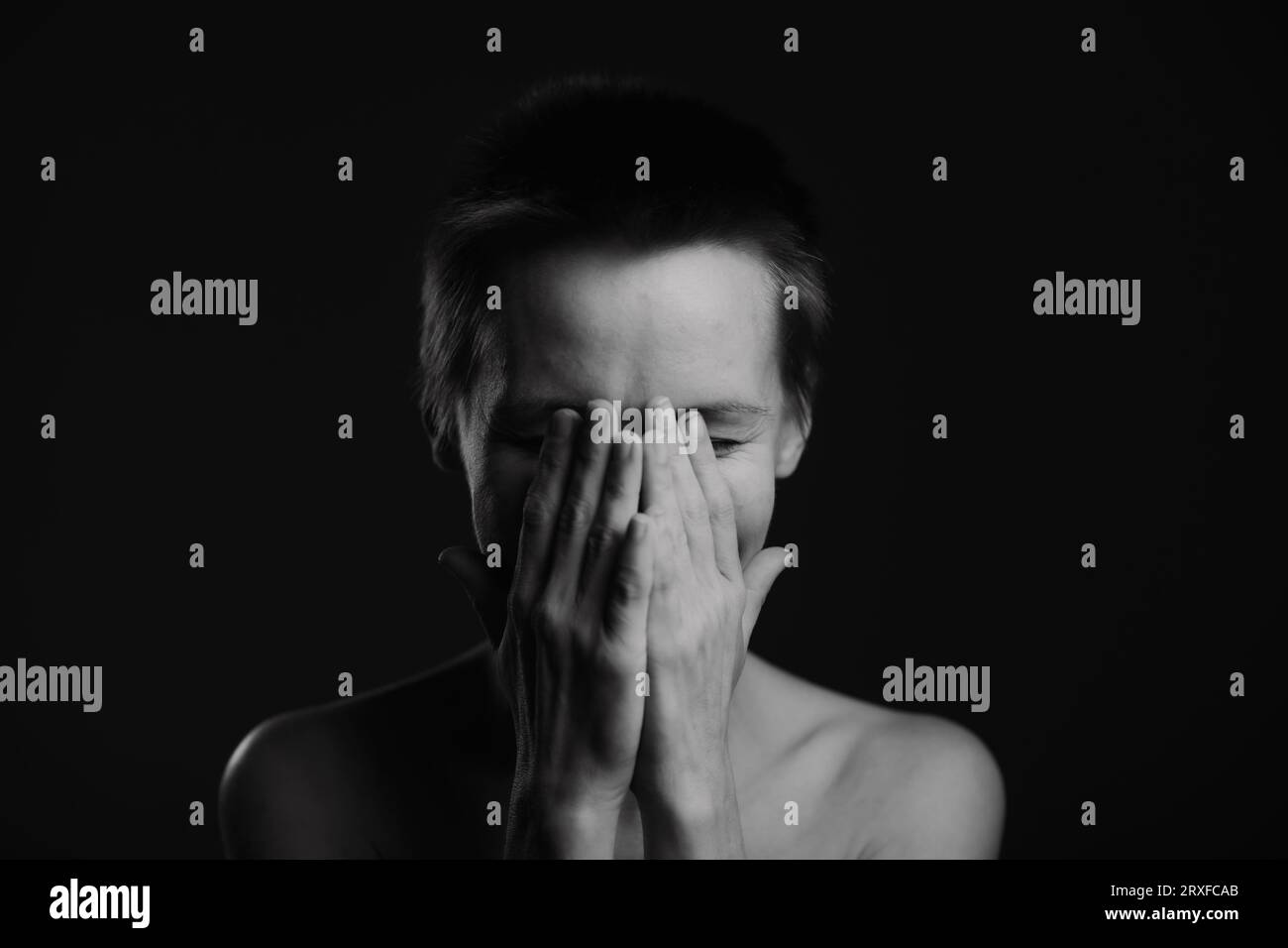 Black and white image of woman covering her face with her hands;. Dark ...