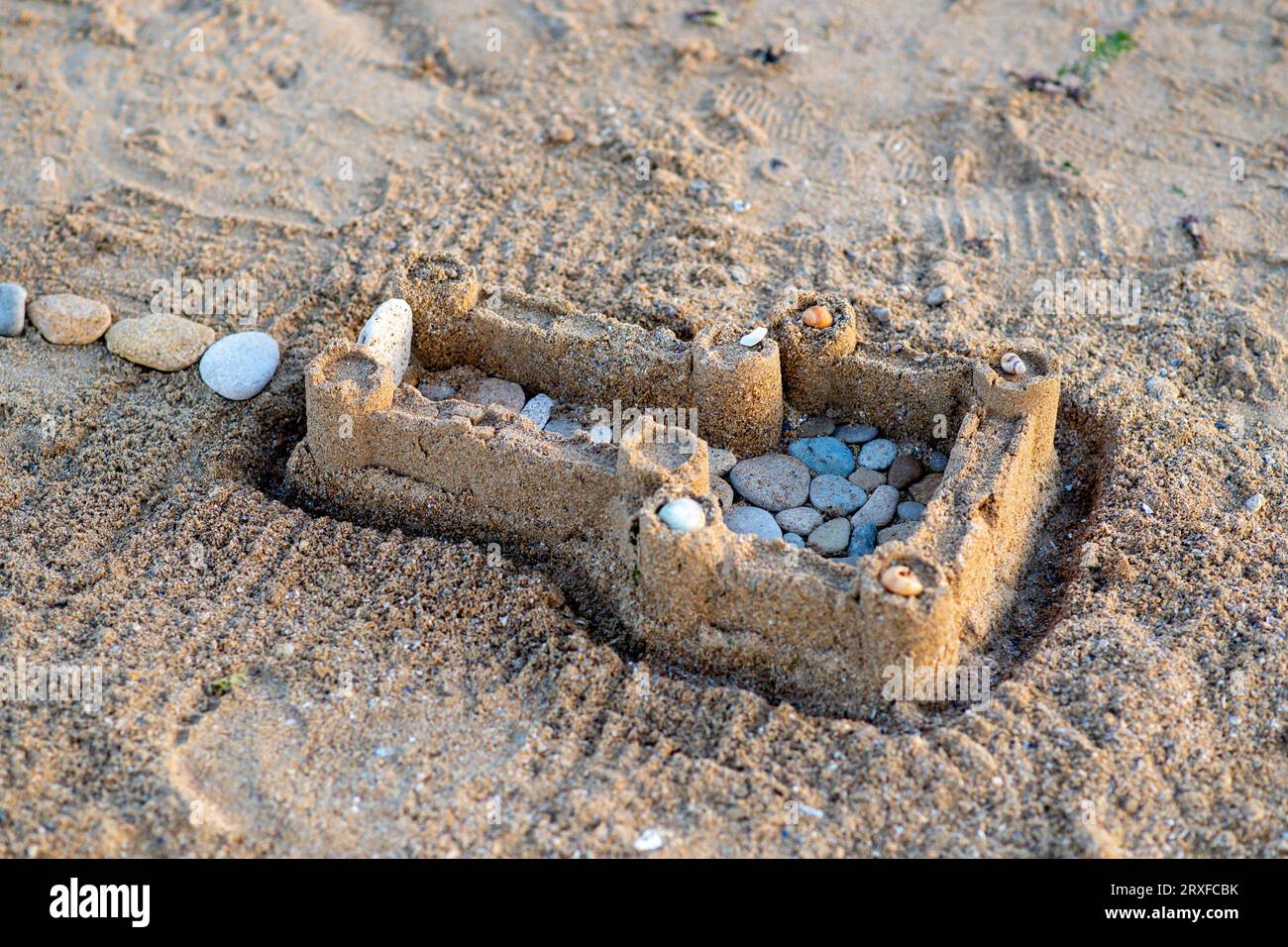 Children's sand castle on beach. Summer vacation. Sea stones and shells ...