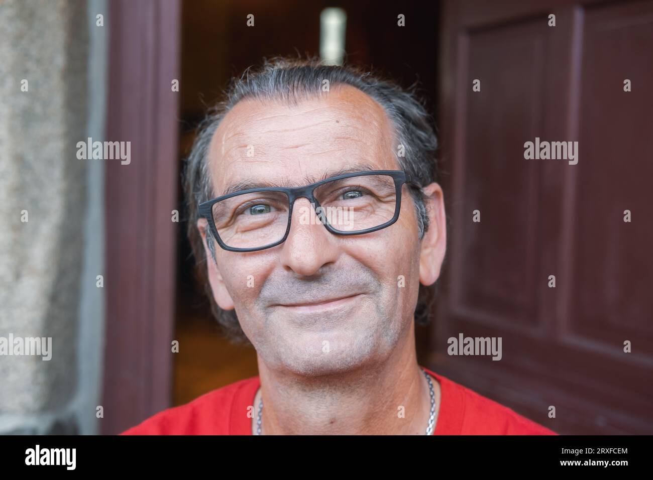 An older man smiles and looks at the camera wearing glasses. Satisfied ...