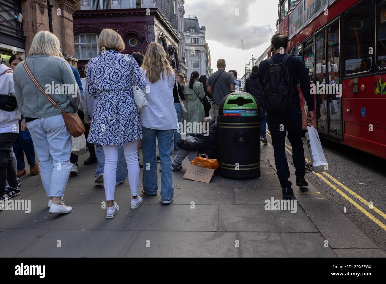 Pedestrians on a busy Oxford Circus high street walk past a homeless ...