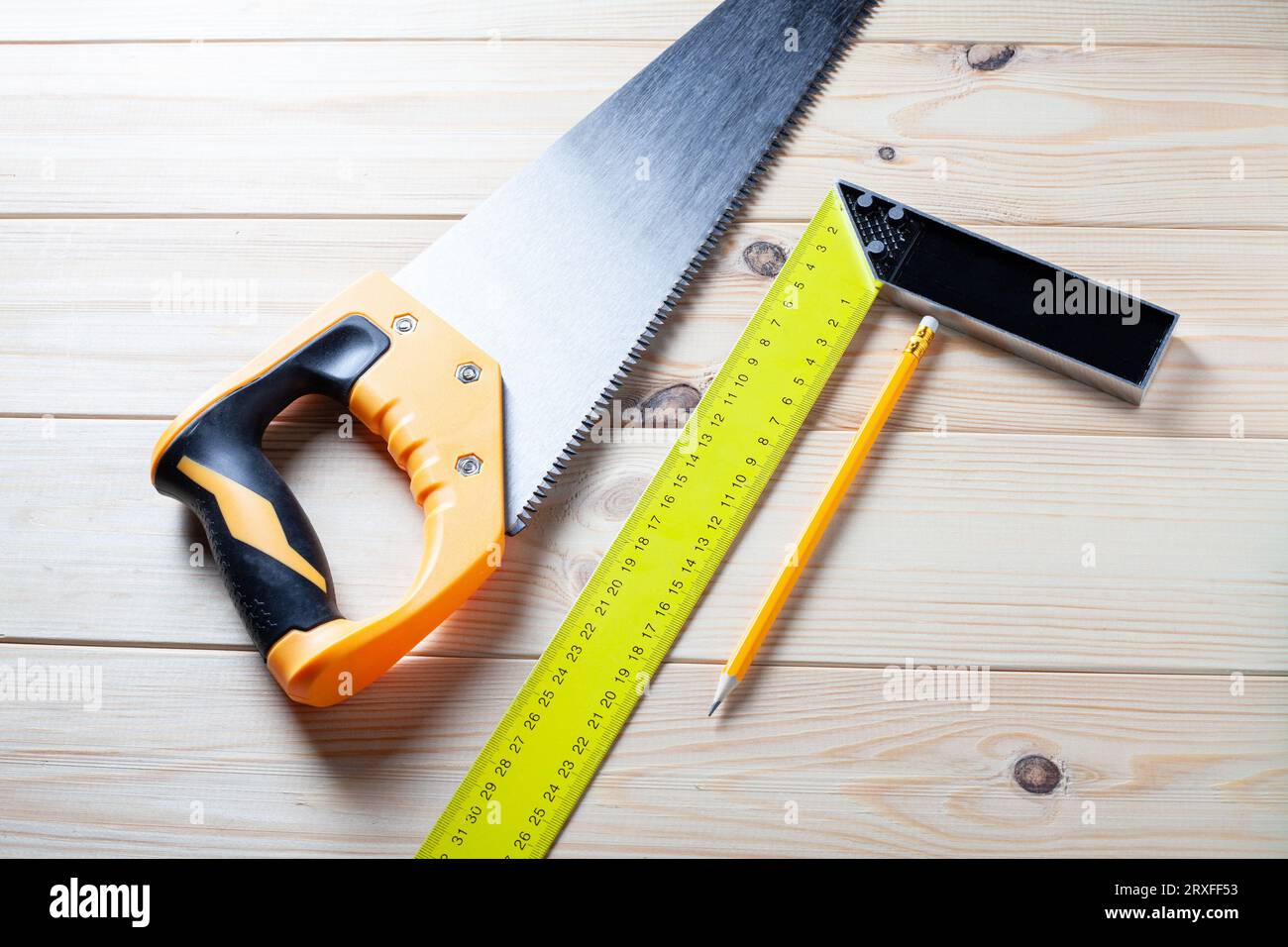 Hand saw, square ruler and pencil for measuring on wooden board ...