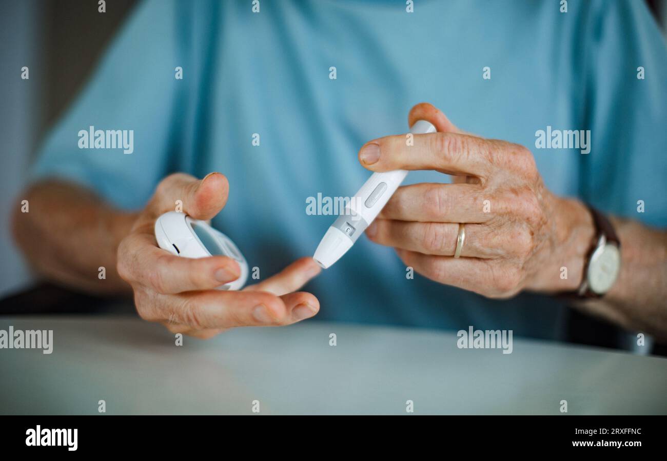 Diabetic senior man on wheelchair checking blood sugar level with ...
