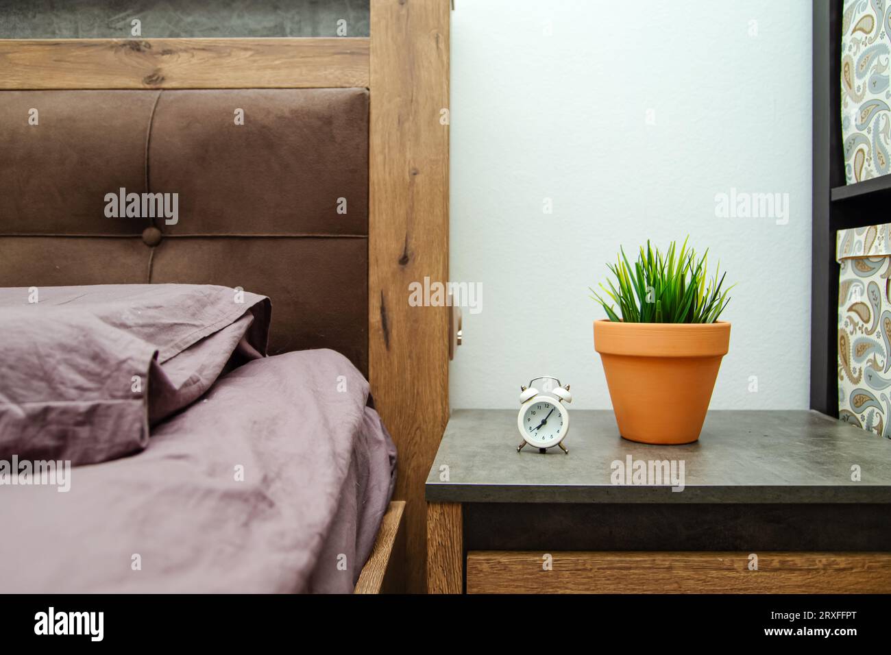 Alarm clock on the bedside table by the bed. Modern bedroom interior ...