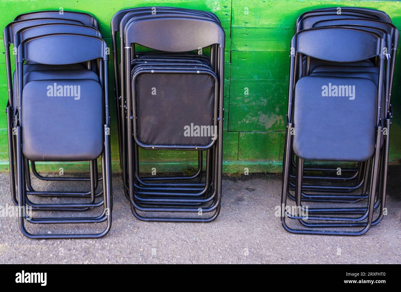 Black seats that fold. Folded chairs on a green background Stock Photo ...