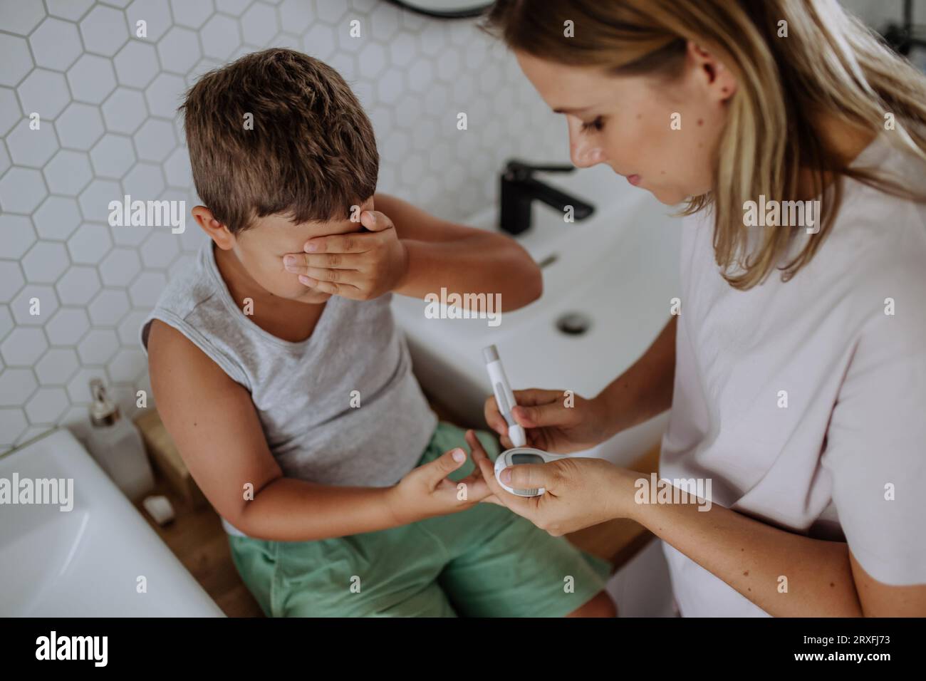 Mother checking her son's blood glucose level at home using a ...