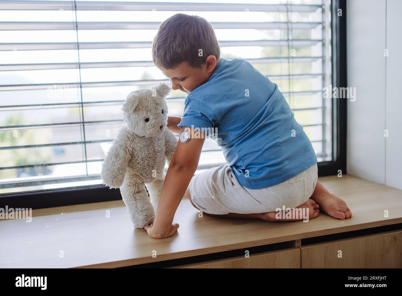 Diabetic boy with a continuous glucose monitor sitting by the window ...