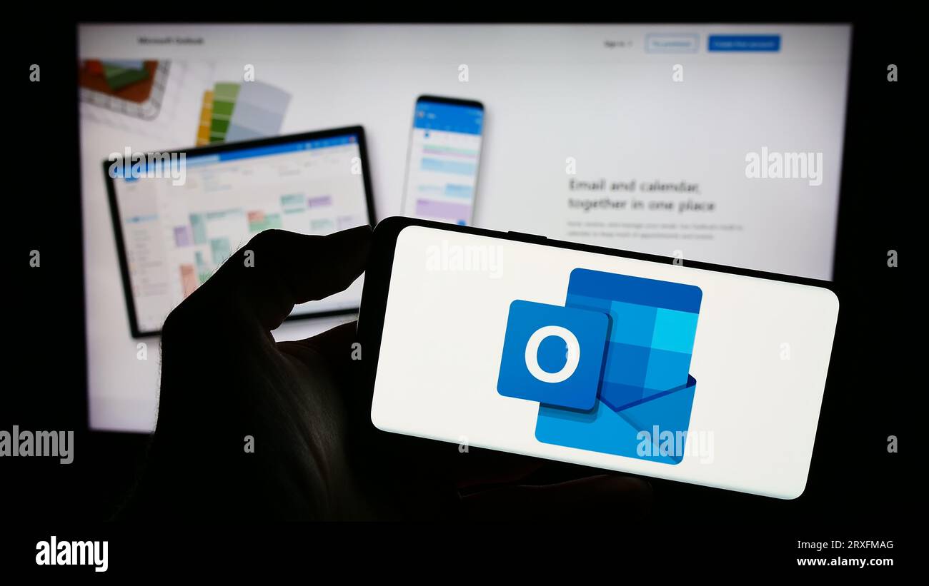 Person holding mobile phone with logo of email software Microsoft ...