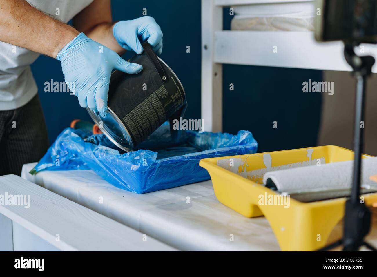 man pouring blue paint from metal jar into in a tray. Renovation home ...