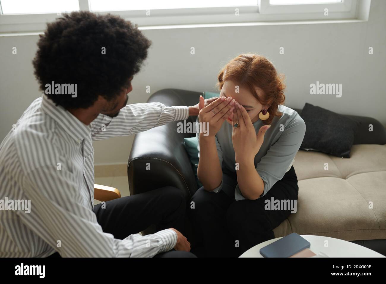 Young woman covering her face with hands when crying talking to her ...