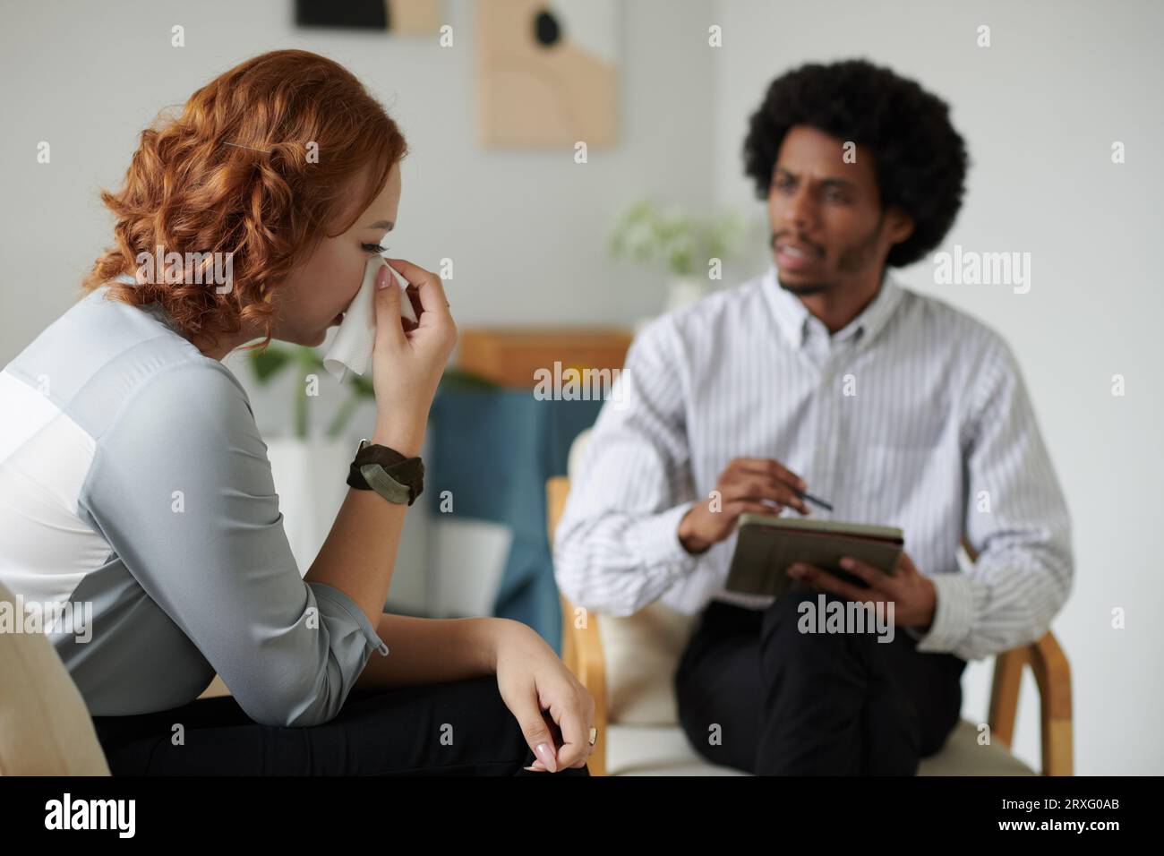 Young woman wiping tears when talking to her Stock Photo - Alamy