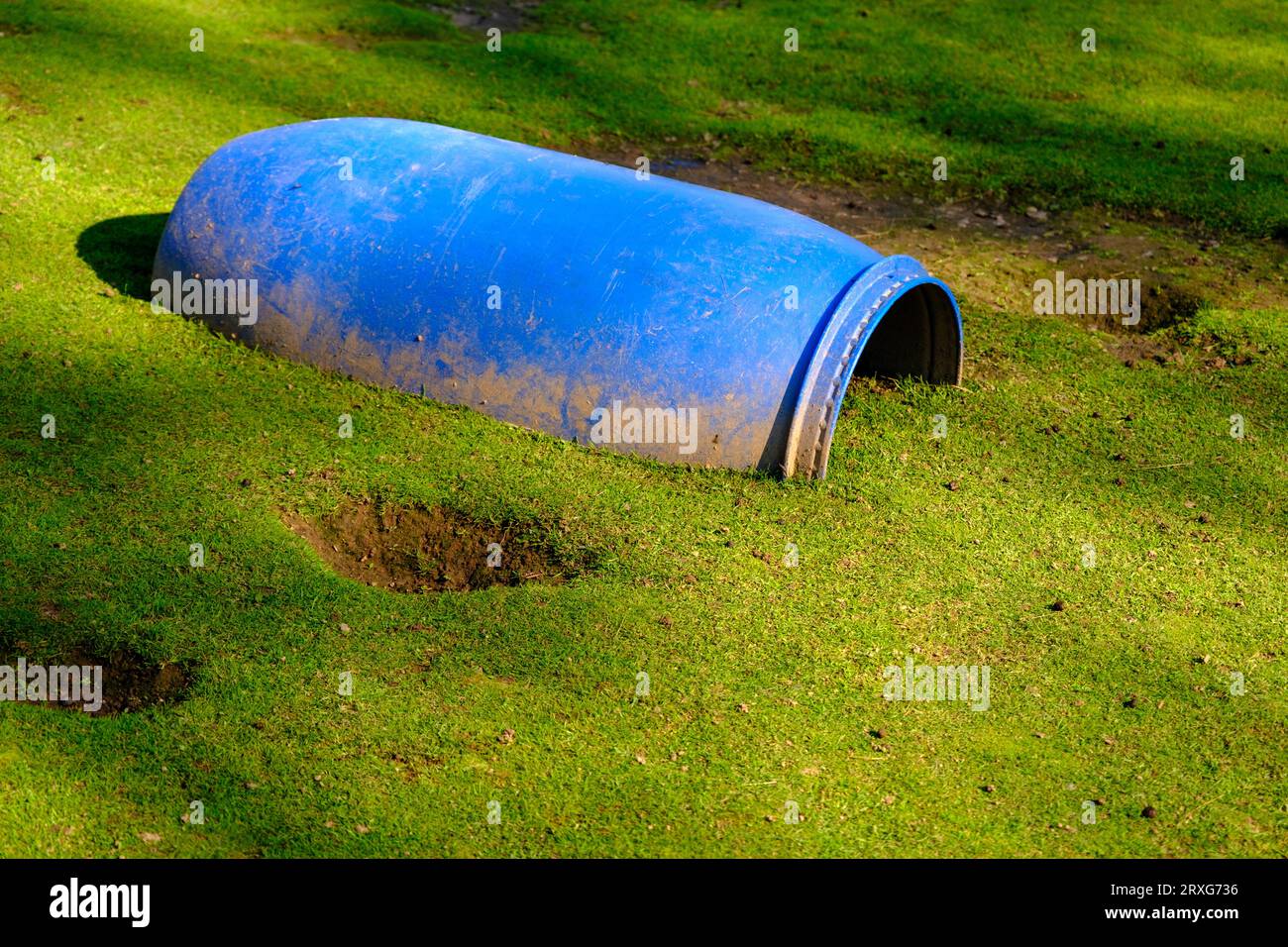 A large blue plastic barrel half buried in the ground. A place for ...
