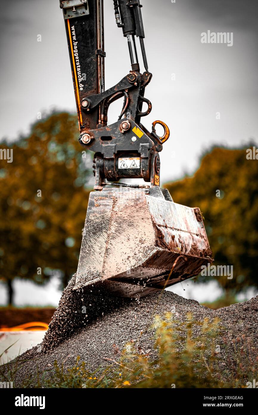 Excavator shovel unloads gravel on construction site Stock Photo - Alamy
