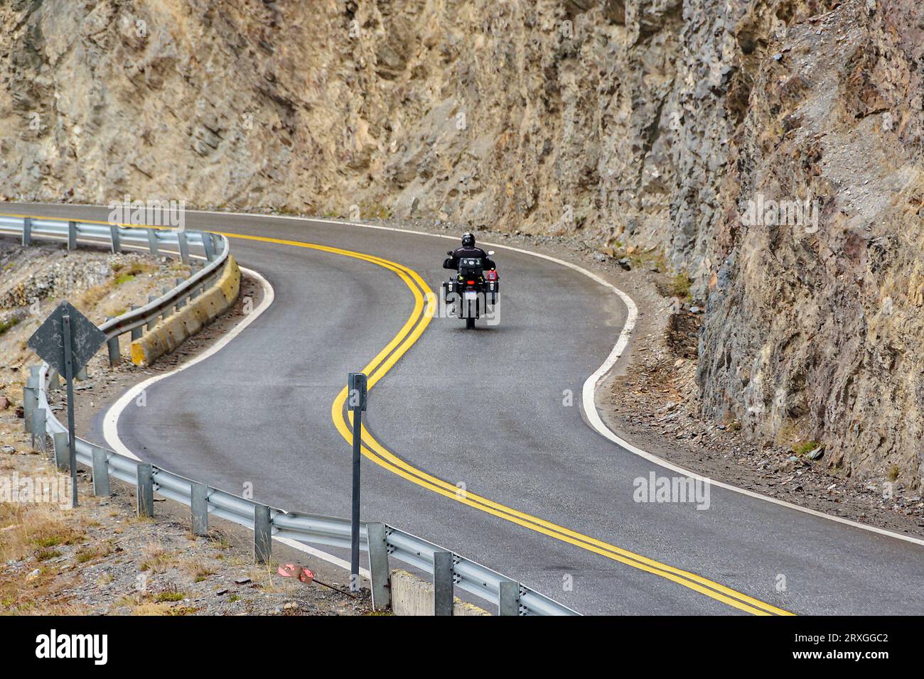 Biker on chopper at highway surrounded by big rocky mountains, tierra ...