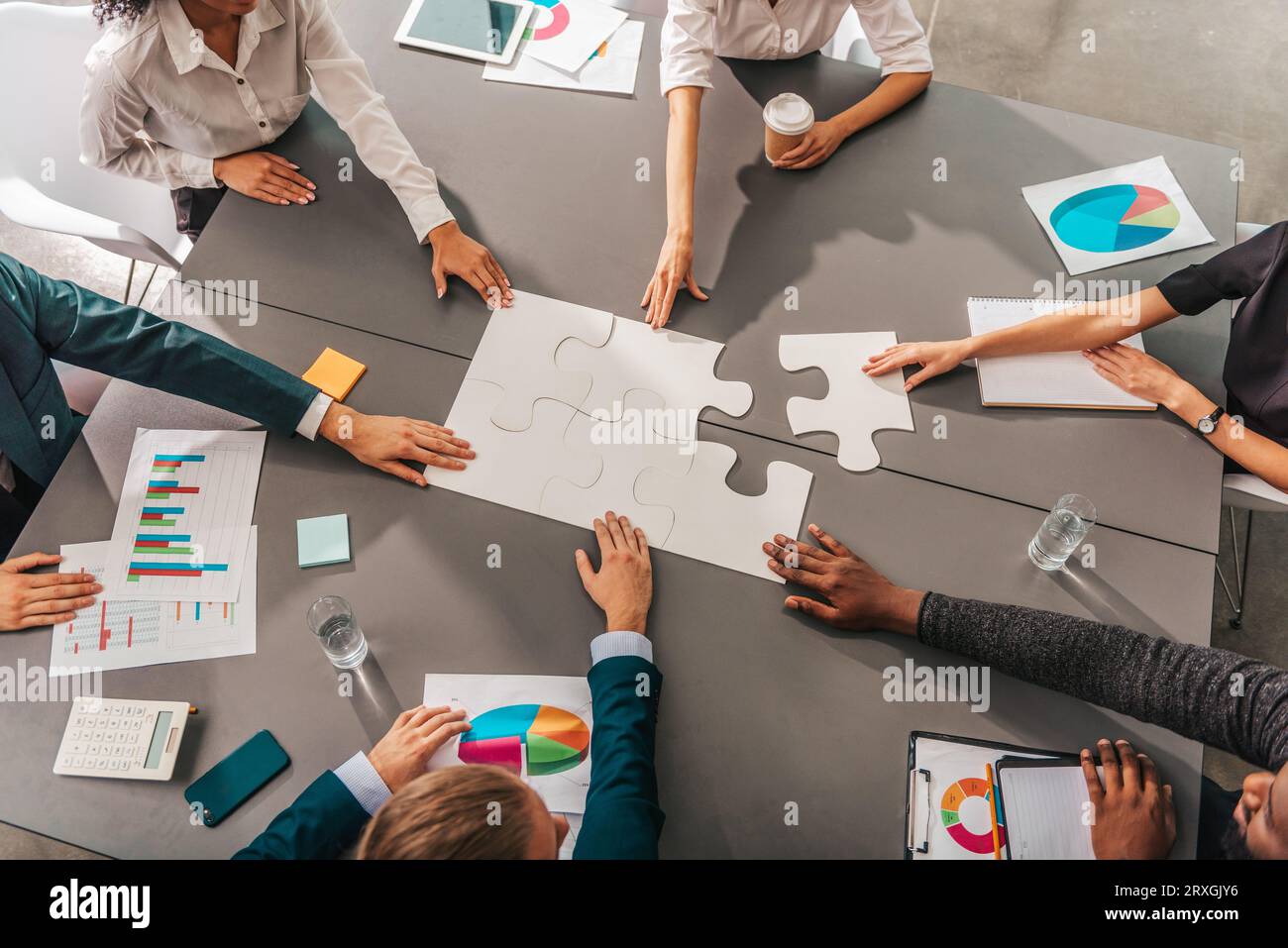 Businessmen working together to build a puzzle as teamwork, partnership and integration concept ...