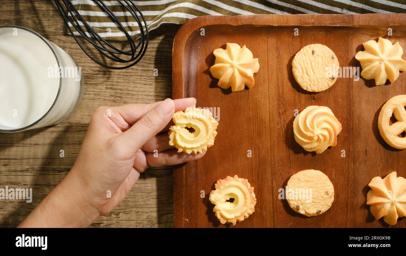 Crop woman taking cookies from wood tray Stock Photo - Alamy