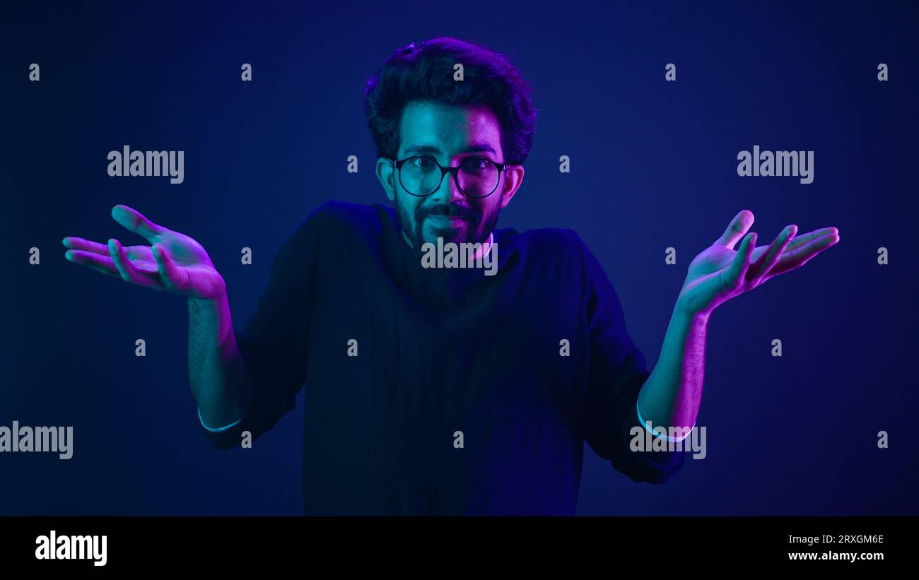 Male portrait in blue neon ultraviolet background Indian man shrug ...