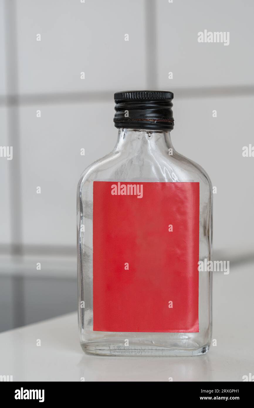Flat empty glass bottle with empty red label on a kitchen counter ...