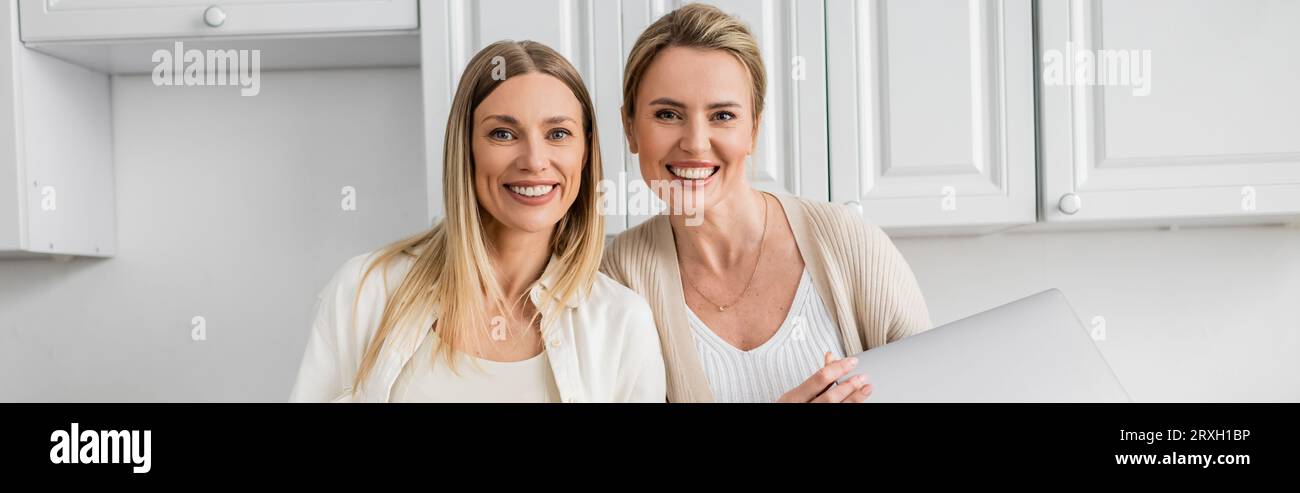 two attractive blonde sisters smiling sincerely and looking at camera ...