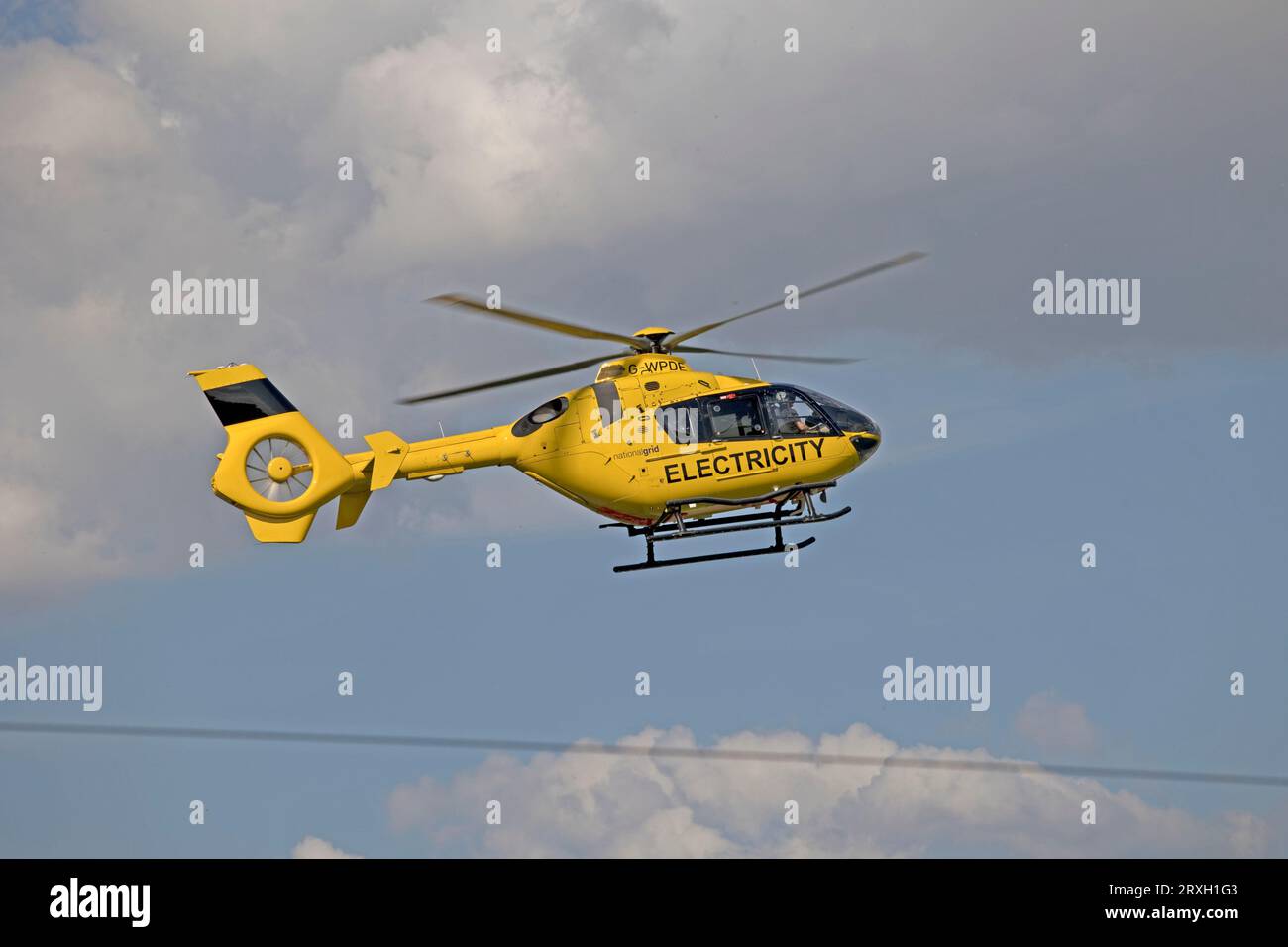 Bright yellow National Grid Electricity helicopter in flight checking ...