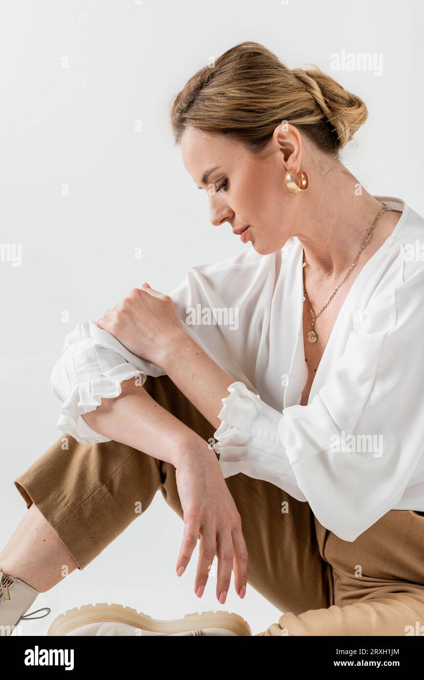 elegant pretty woman in formal pastel wear sitting on floor and looking ...