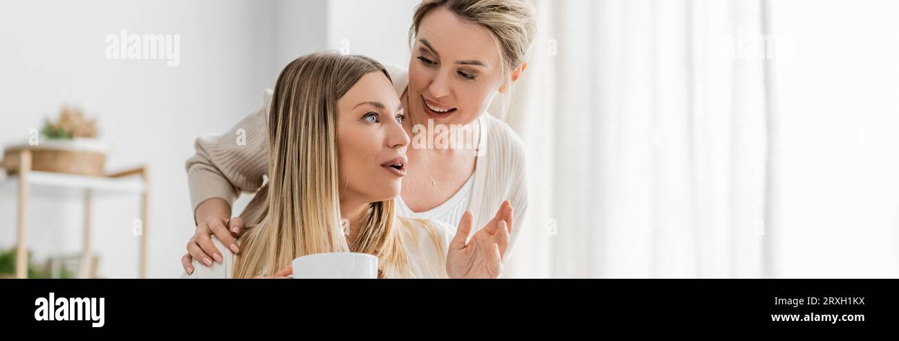 close up blonde attractive sisters talking and smiling on kitchen ...