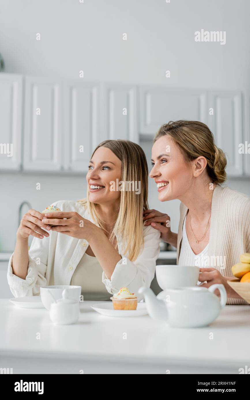 classy blonde sisters in pastel cardigans savoring cupcakes and tea and ...