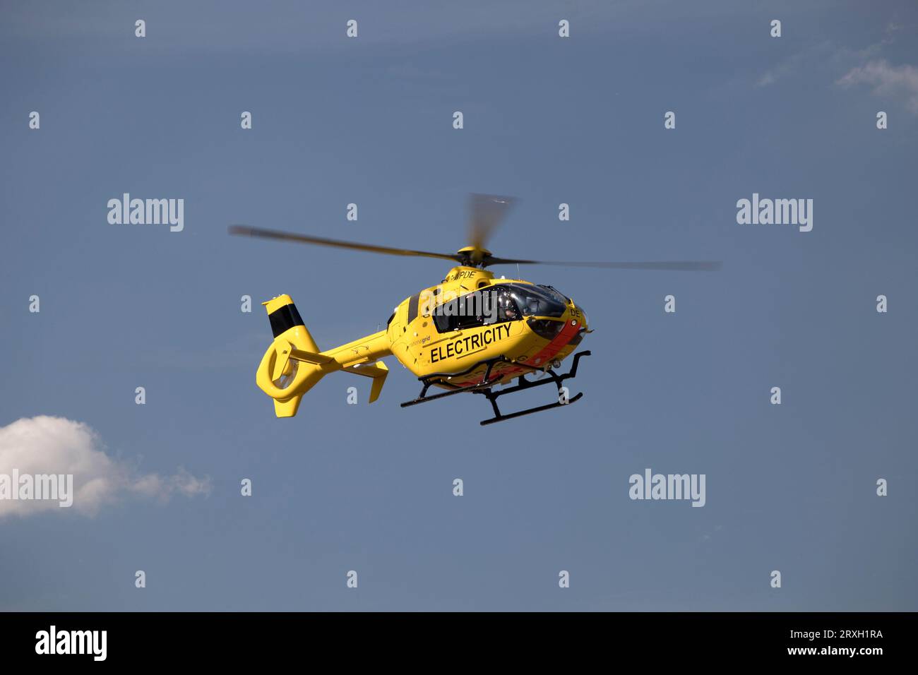 Bright yellow National Grid Electricity helicopter in flight checking ...