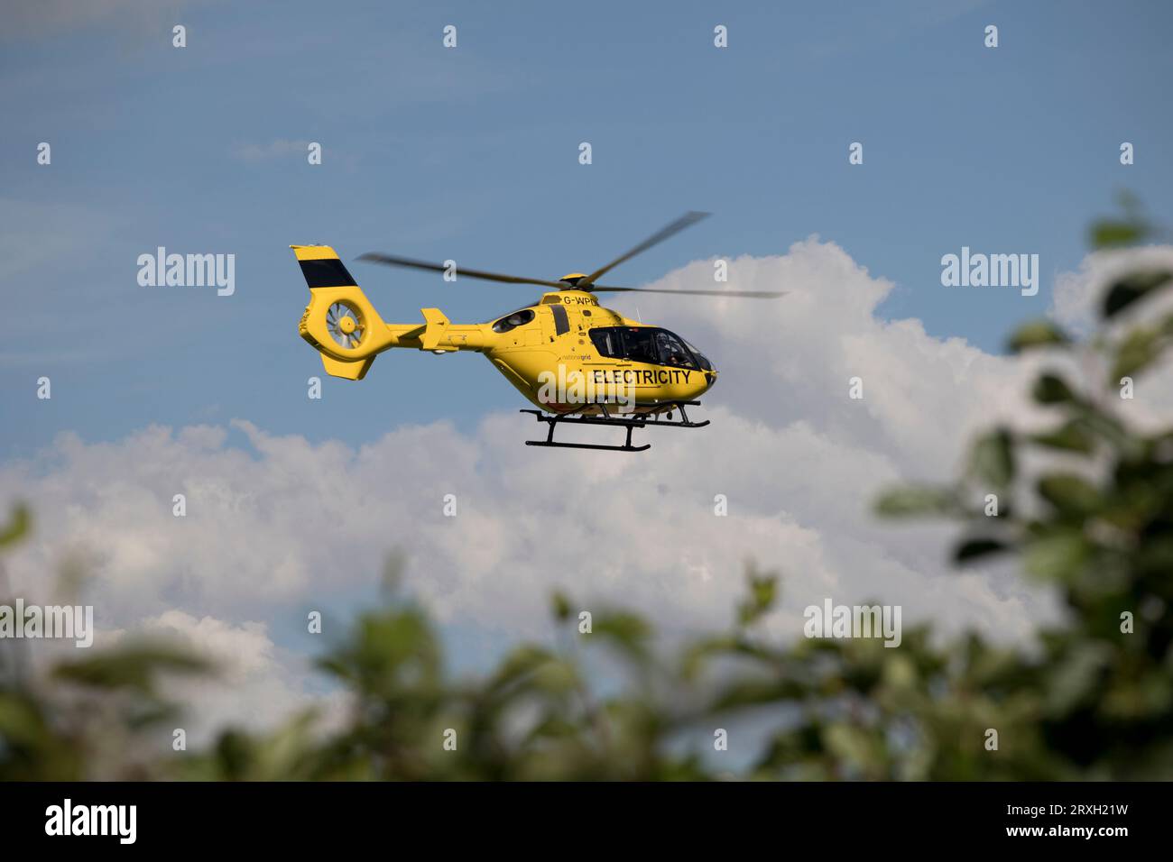 Bright yellow National Grid Electricity helicopter in flight checking ...