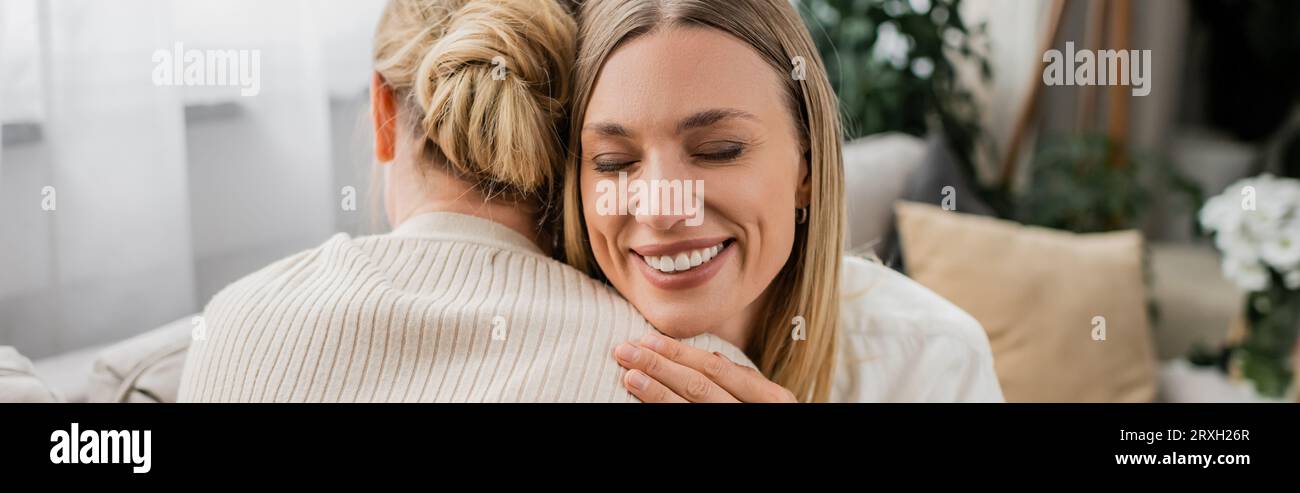 lovely pretty sisters in casual attire hugging and smiling sincerely ...