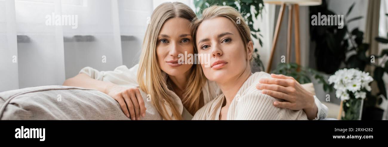 portrait of classy sisters in trendy attire hugging looking at camera ...
