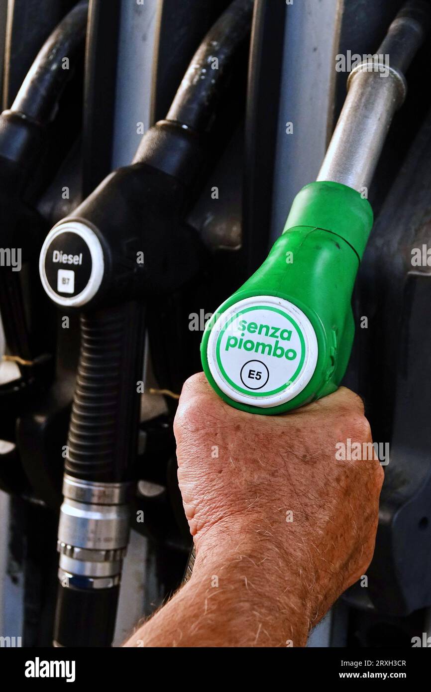 Hand of a man holding a green gasoline pump bearing the inscription ...