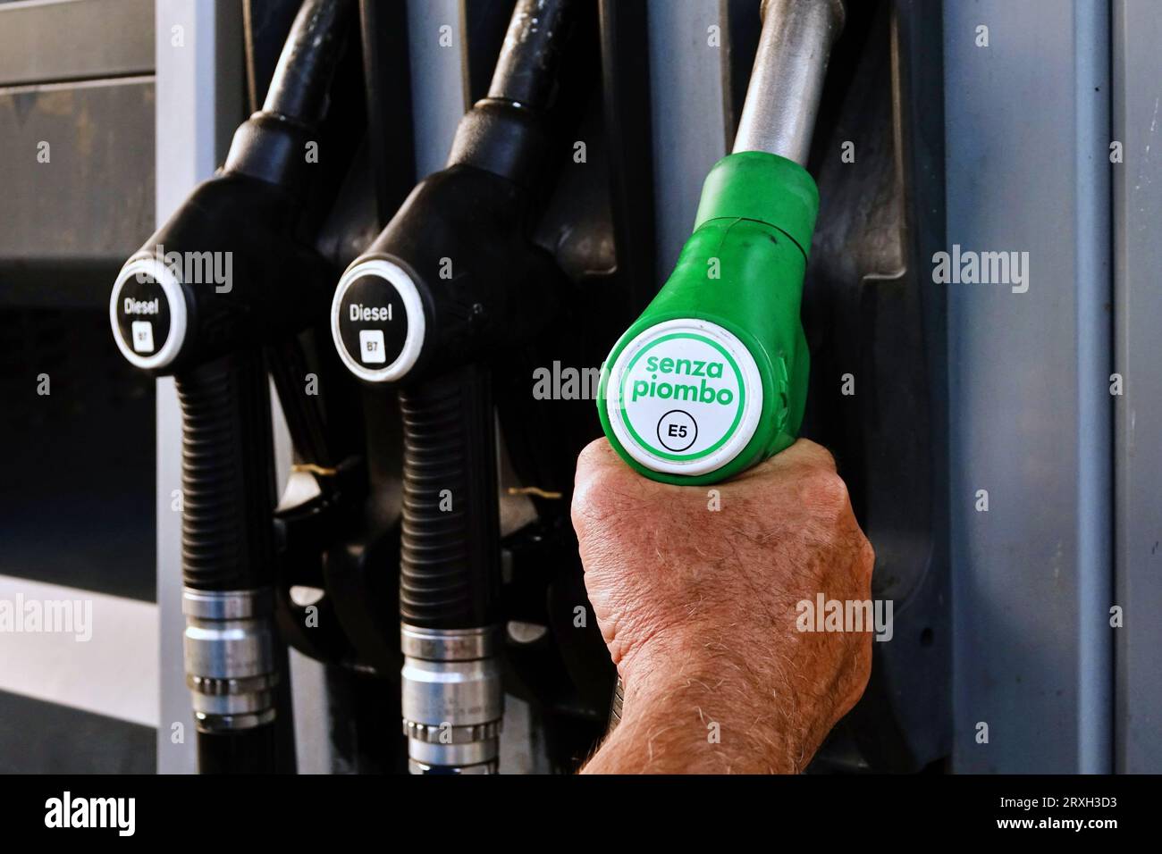 Hand of a man holding a green gasoline pump bearing the inscription ...