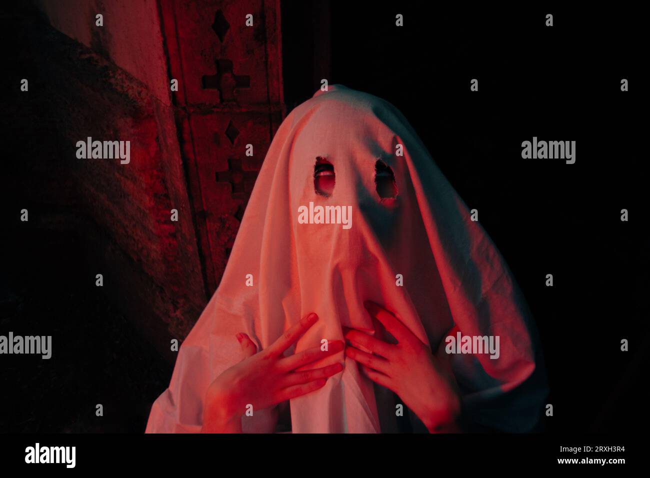 A woman dressed in a creepy ghostly outfit with eye holes rolled back ...