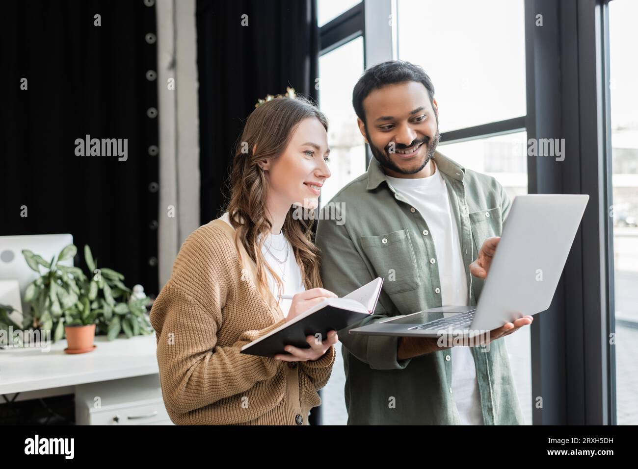 happy indian businessman showing project on laptop to female coworker ...