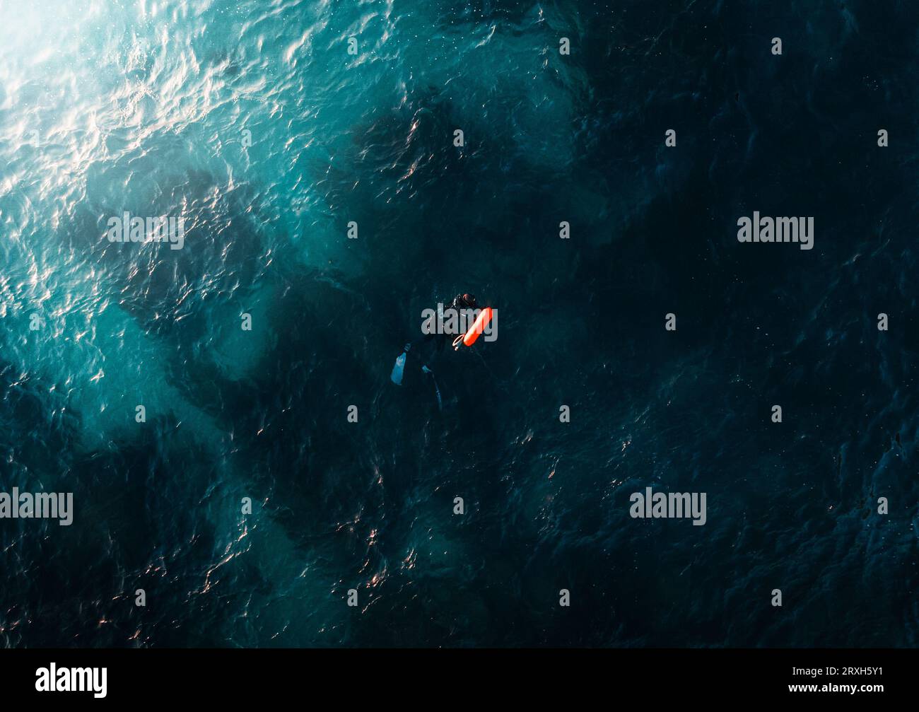 Aerial photo (top view) of diver with orange swimming buoy (bag) on the ...