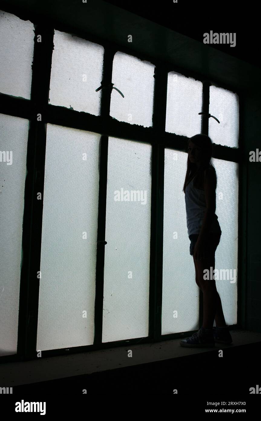 Teen in depression in an empty abandoned room. Bright light from window ...