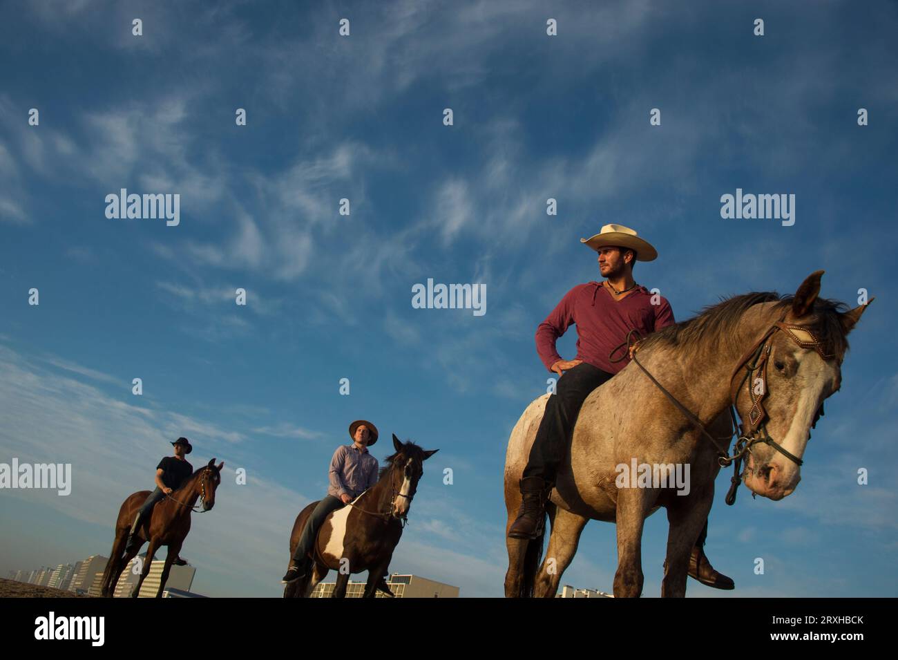 Three cowboys ride their horses at sunrise along Virginia Beach in ...