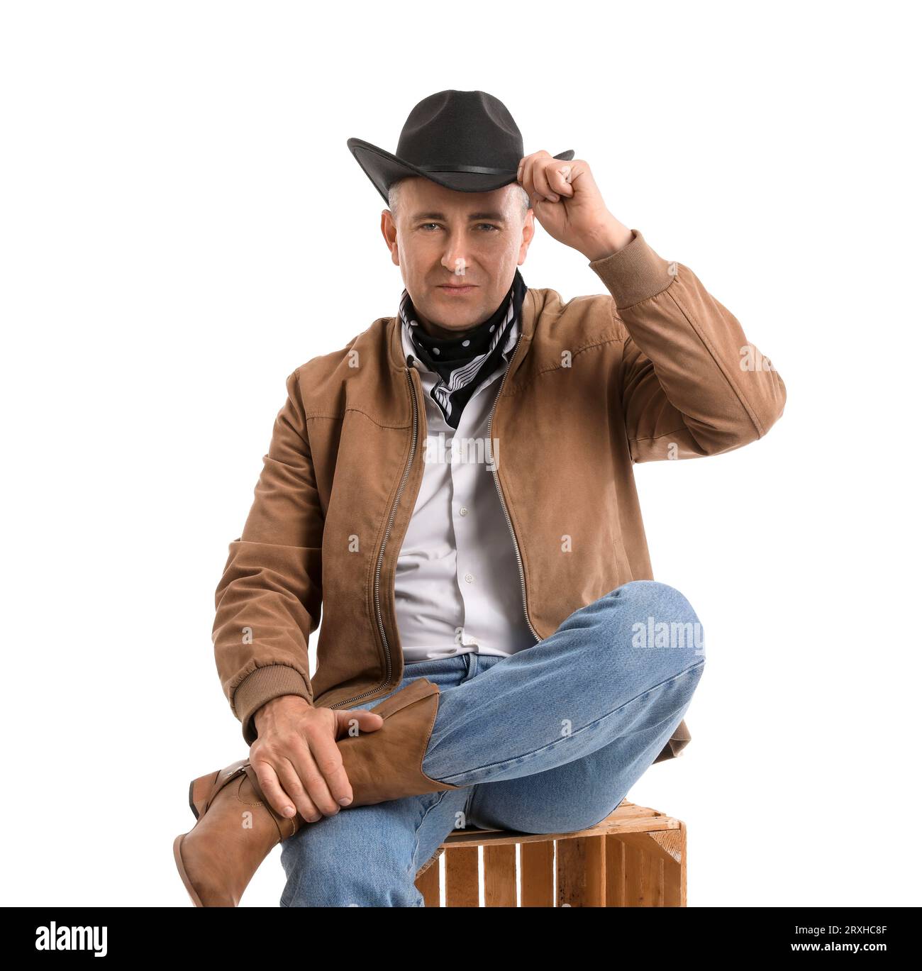 Mature cowboy sitting on white background Stock Photo - Alamy