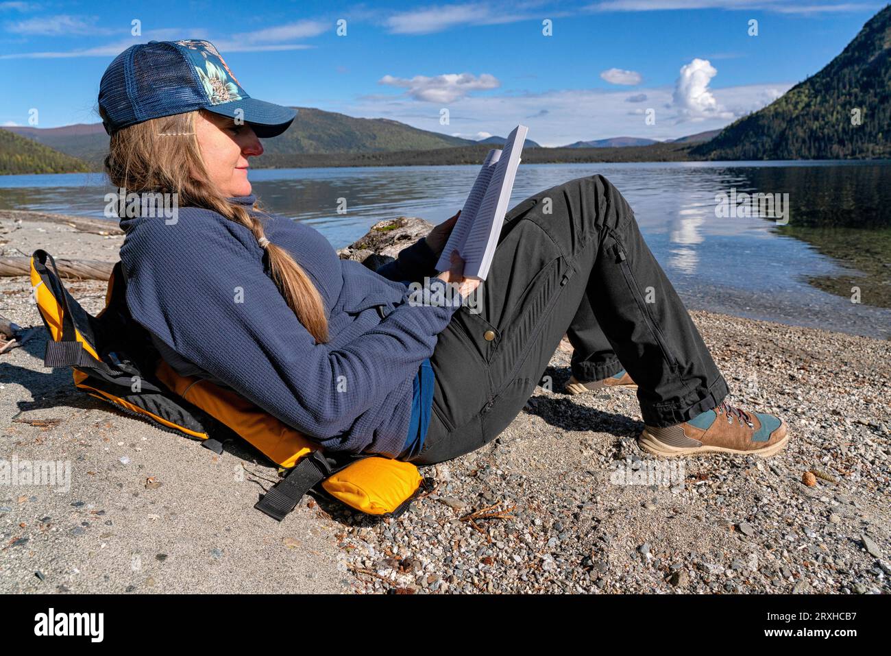 Woman living her best life reading a book on the shores of a remote ...