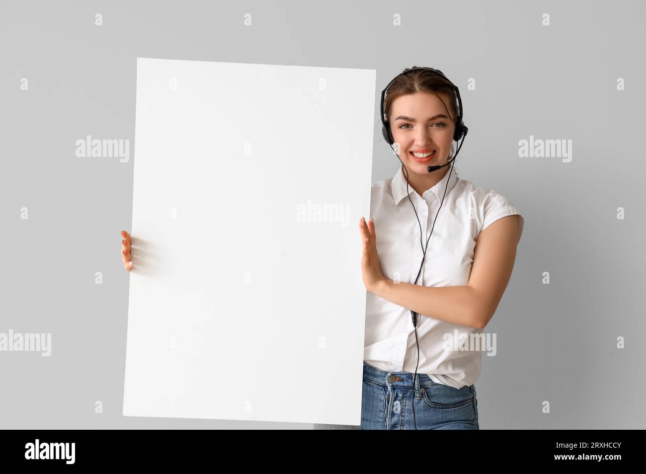 Female technical support agent with blank poster on light background ...