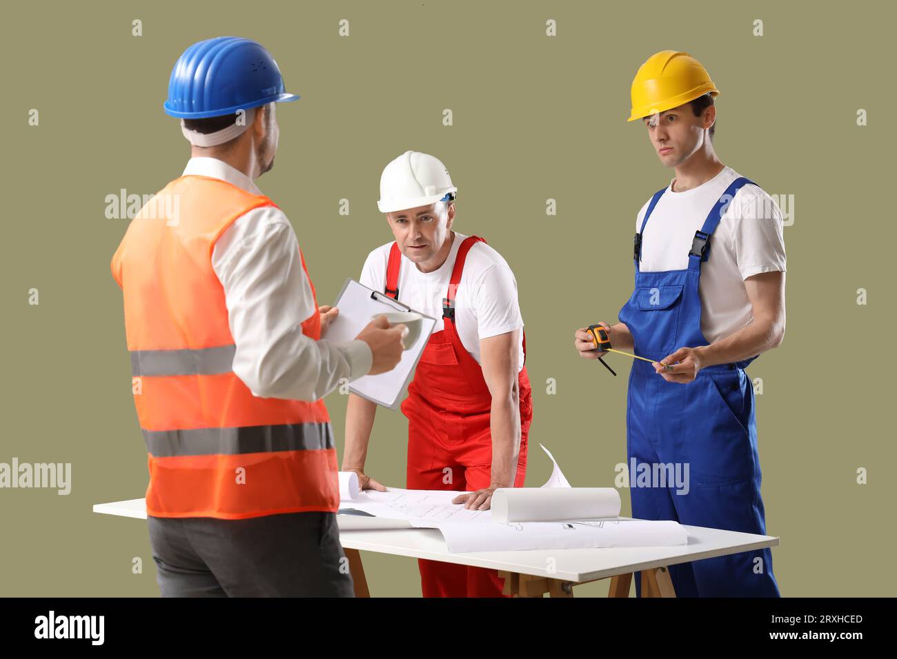 Team of male builders with table on green background Stock Photo - Alamy