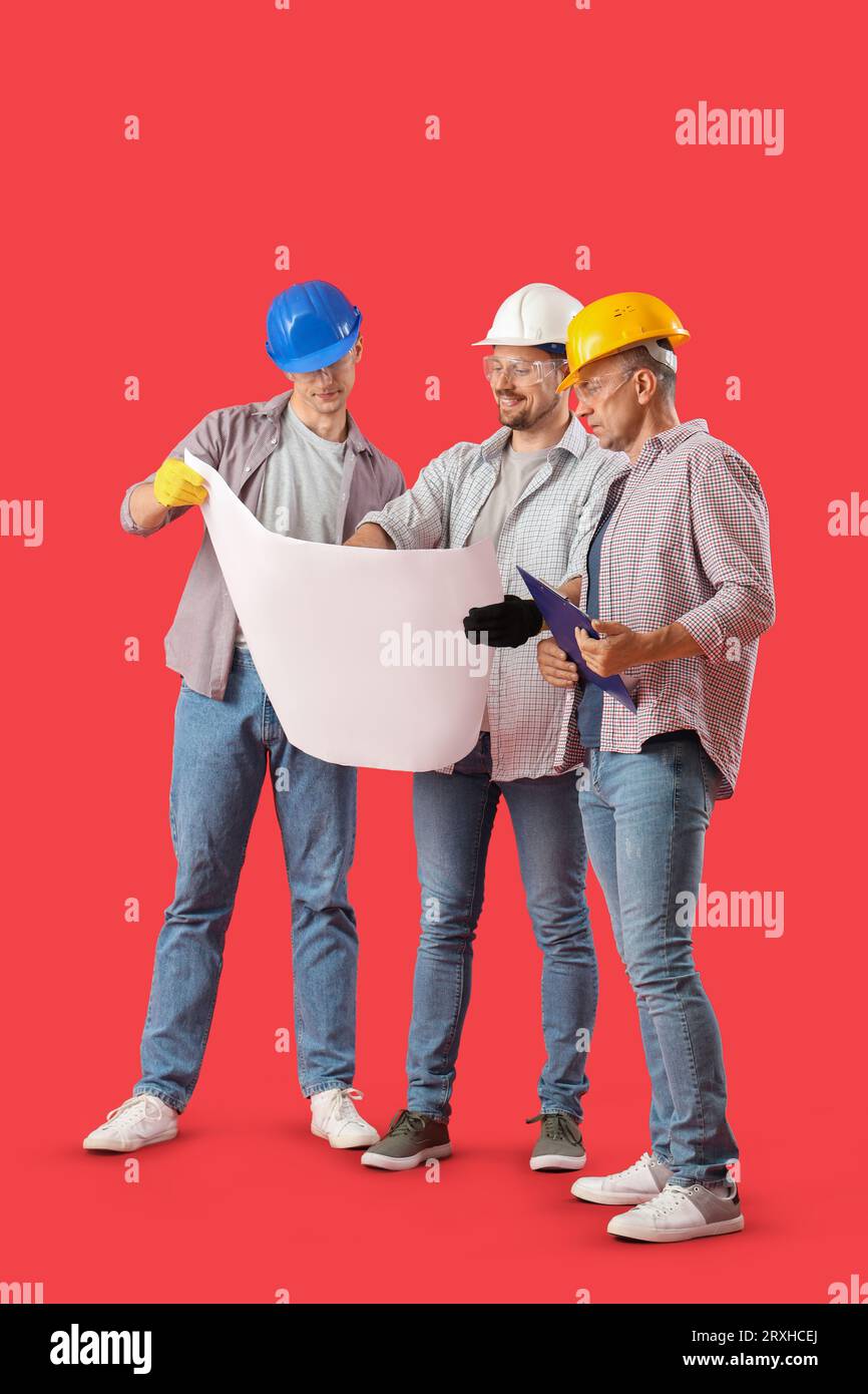 Team of male builders with house plan on red background Stock Photo - Alamy