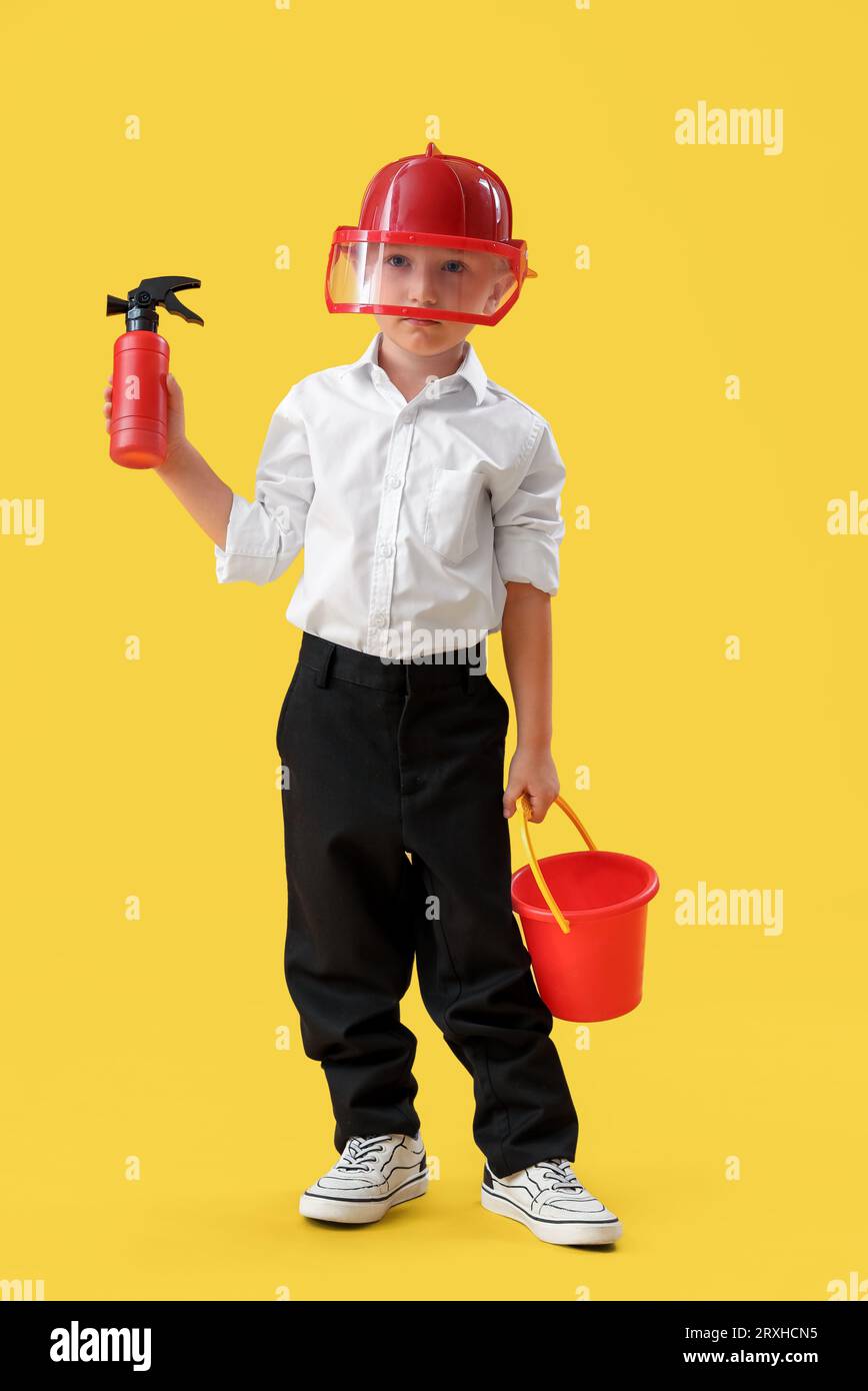 Cute little firefighter on yellow background Stock Photo - Alamy