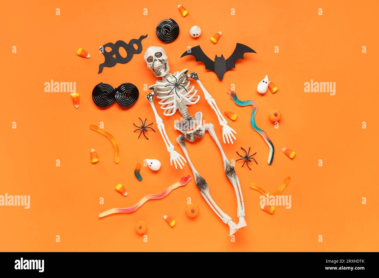 Halloween composition with skeleton and candies on orange background ...