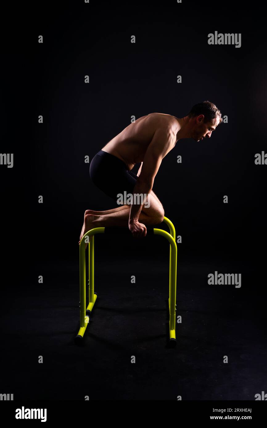 Front and side view photo of an strong young man exercising on parallel ...