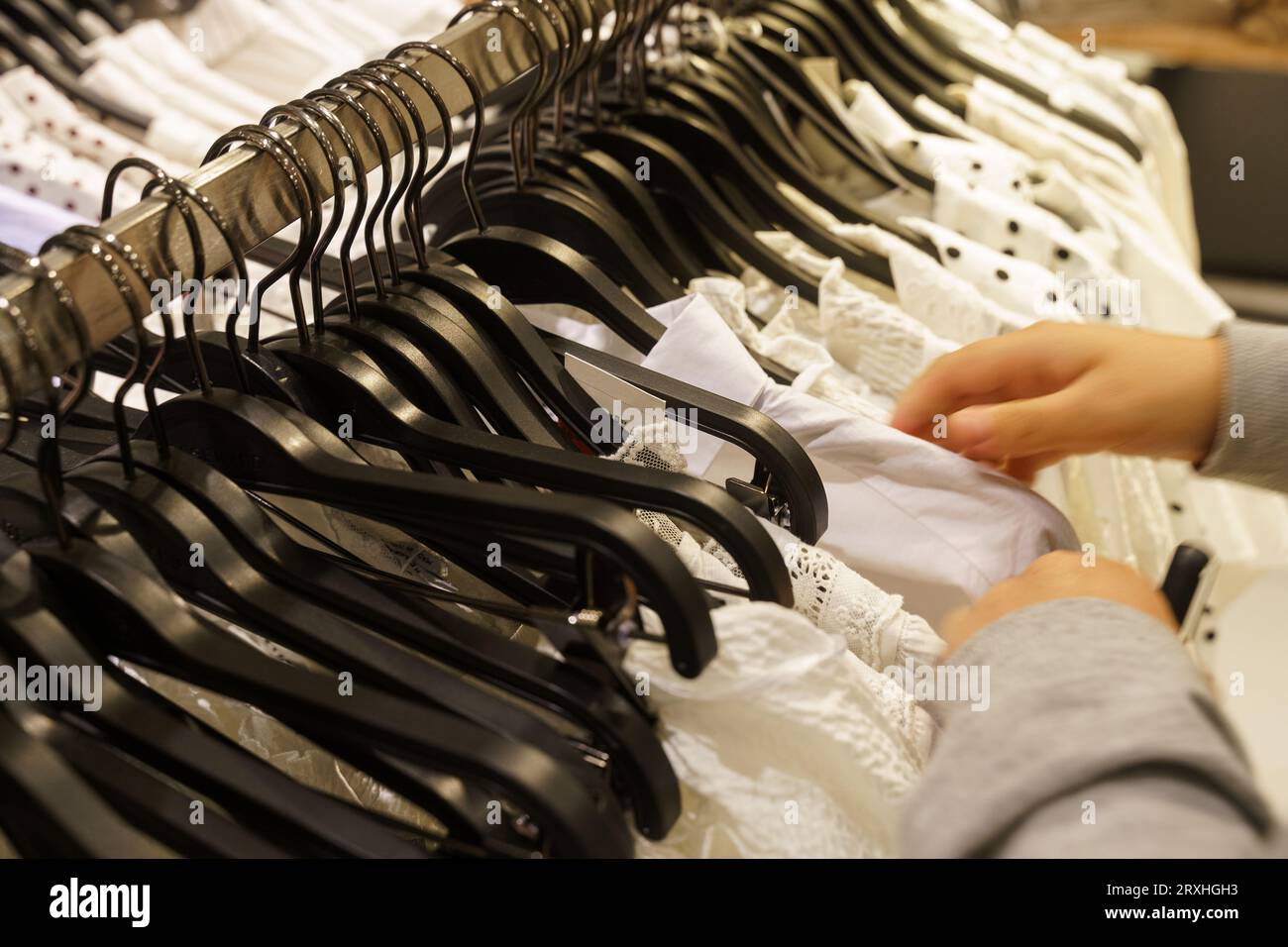 A woman chooses a blouse that hangs on a hanger in a clothing store ...