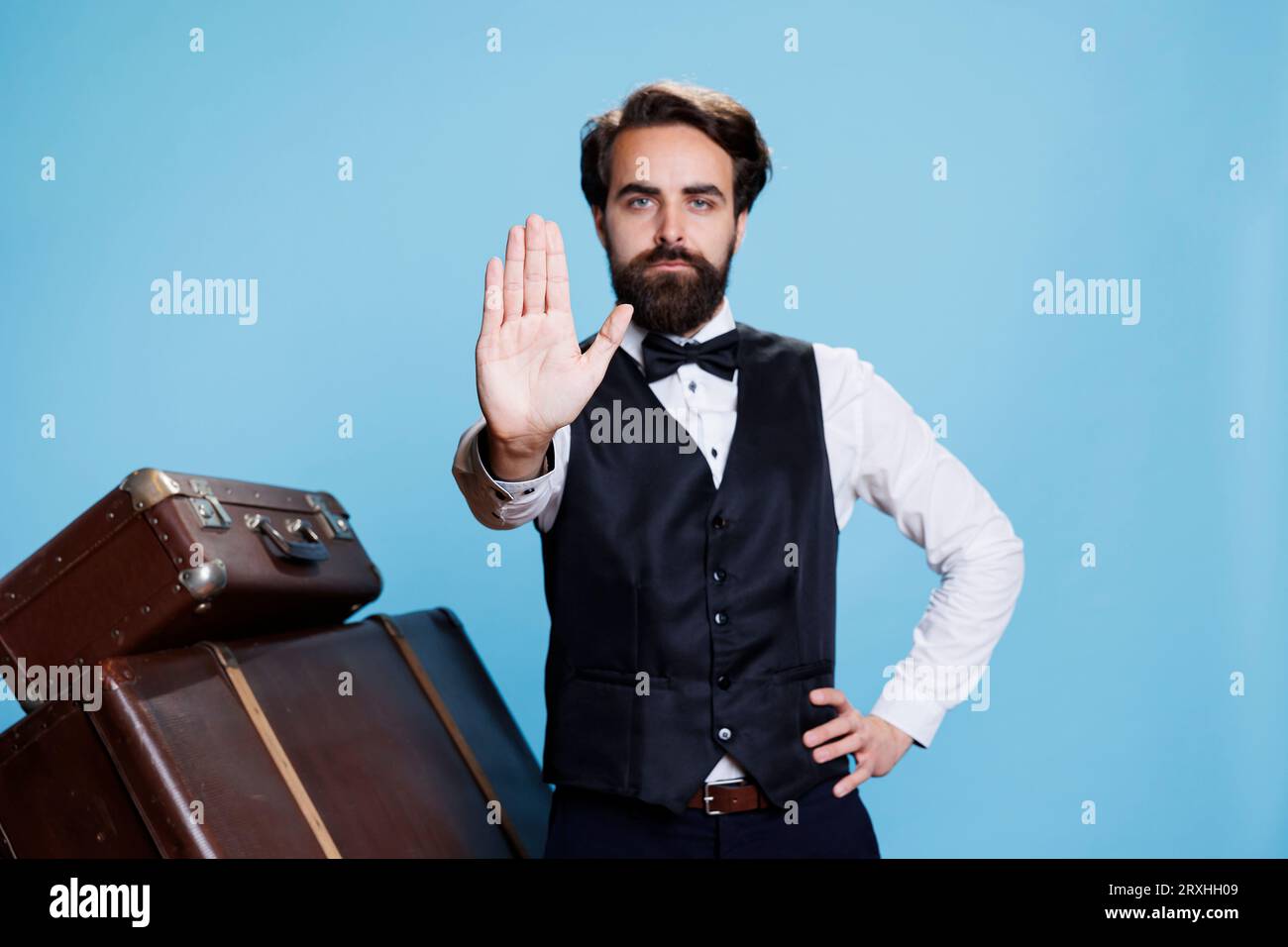 Man raises hand to indicate stop sign against blue background, creating ...