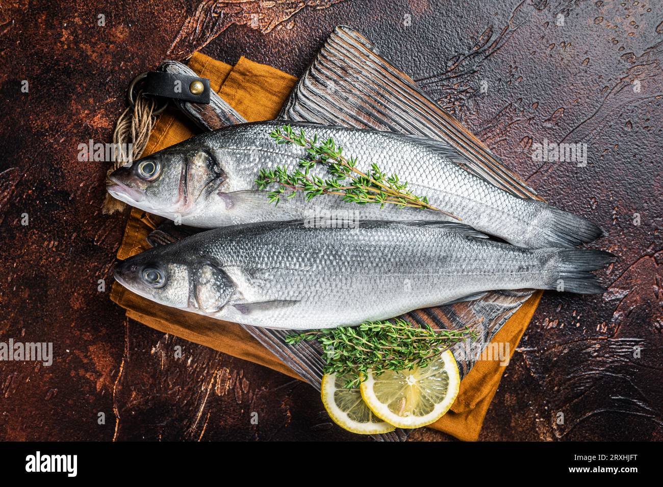 Raw Sea Bass, Branzino fish with thyme and lemon. Dark background. Top ...